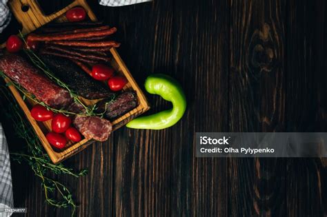 녹색 종이와 토마토가 든 나무 쟁반에 다양한 종류와 크기의 소시지 어두운 배경에 훈제 소시지 세트 가공육에 대한 스톡 사진 및