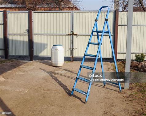 푸른 금속 사다리가 하얀 통 옆의 마당에 서 있고 태양의 밝은 광선 아래 서 있다 0명에 대한 스톡 사진 및 기타 이미지 0명 Diy 가정 생활 Istock