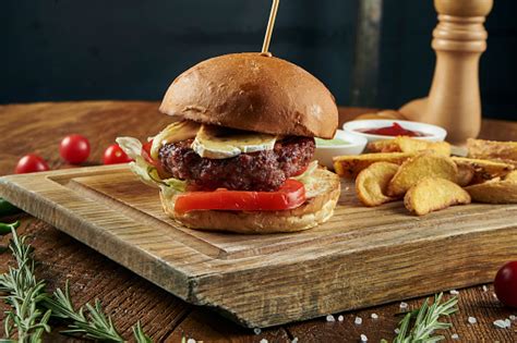 크래프트 브라운 페이퍼에 감자 튀김과 치즈 버거에 대한 보기를 닫습니다 전통적인 패스트 푸드 양상추 토마토 치즈 오이와 신선한 맛있는 햄버거 디자인을 위한 공간을 복사합니다