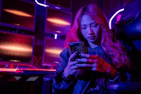 Asian Woman In Front Of A Computer Monitor Display Using Mobile Phone Neon Stock Image Image