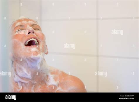 Happy Hispanic Woman Laughing As She Enjoys A Shower Covered In Soap Suds With Her Face Raised