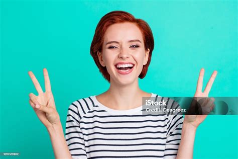 그녀의 그녀가 좋은 귀여운 매력적인 매력적인 명랑 다행 낙관적 빨간 머리 여자의 밝은 선명한 빛 녹색 청록색 배경 위에 절연 이중 Vsign를 보여주는 줄무늬 스웨터에