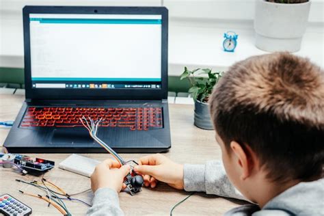 Premium Photo A Boy Plugging Cables To Sensor Chips While Learning Arduino Coding And Robotics