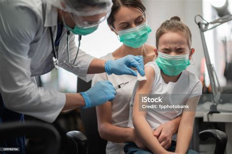 돌보는 어머니가 예방 접종을 받기 위해 딸을 예방 접종 사무실로 데려 왔고 소녀는 두려워합니다 개발에 대한 스톡 사진 및 기타