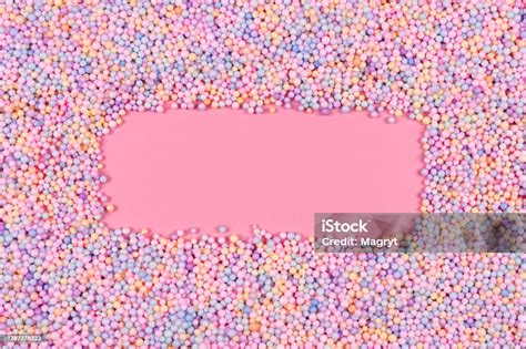 핑크에 파스텔 컬러 볼로 만든 프레임 스티로폼 또는 폴리스티렌 폼 배경 과자 장식을위한 다채로운 설탕 공의 혼합 무지개 색 설탕 칩 드래그 스핀 과자 구에 대한 스톡 사진