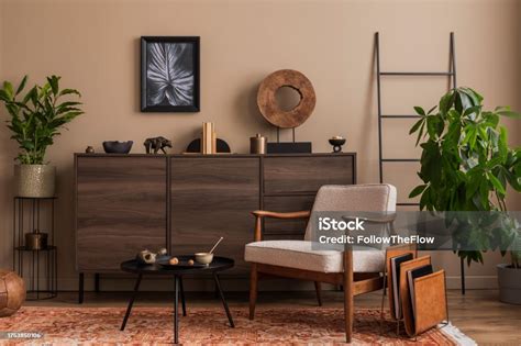 모형 포스터 프레임 부클 안락 의자 둥근 커피 테이블 나무 찬장 식물 거실 인테리어의 세련된 구성 가산기 및 개인 액세서리 가정