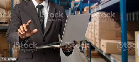 제복을 입은 스토리지 작업자 하드 햇을 착용하고 물품이 담긴 선반으로 가득 찬 소매 창고에서 디지털 태블릿 컴퓨터로 재고 및 재고를 확인합니다 경영자에 대한 스톡 사진 및