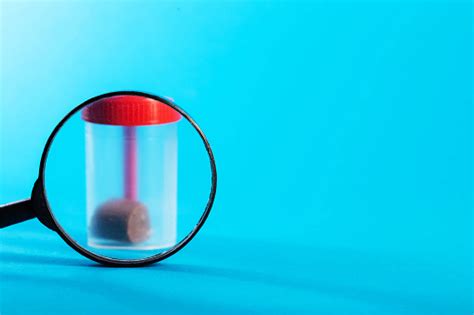 파란색 배경에 대변 분석이 있는 의료 용기 배경의 돋보기 난모세포염 감염 및 Dysbacteriosis에 대한 대변 분석의 개념 텍스트 공간 복사 건강관리와 의술에 대한