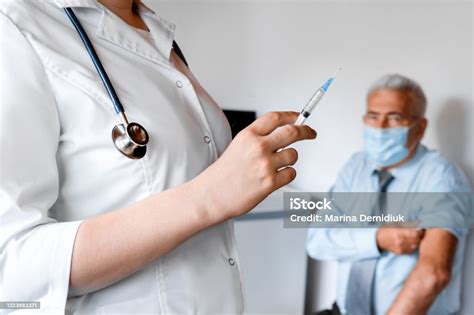 의사 여자는 의료 마스크에 노인에게 주사를 만들기 전에 주사기를 들고 코비드 백신 수석 남자 예방 접종을주는 의사 바이러스 보호 코비드19 코로나바이러스 개념에 맞서