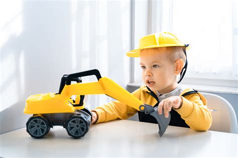 아이들은 집에서 굴삭기를 가지고 놀고 엔지니어가되는 꿈을 꾼다 작은 건축업자 교육 상상력 목적성 개념 굴착기를 가진 소년 흙 파는 기계에 대한 스톡 사진 및 기타 이미지