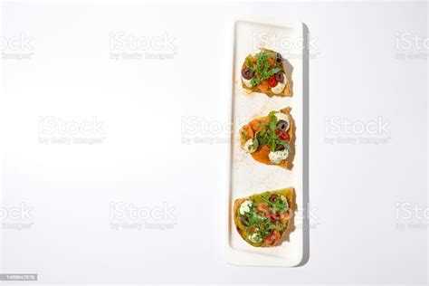 흰색 배경 위에 연어 브루 쉐타와 미적 구성흰색 벽 위에 있습니다 연어 아보카도 치즈 올리브를 곁들인 이탈리아 브루쉐타는 여름에 고급 식사를 합니다 우아한 메뉴 개념 도마