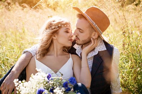 화창한 날에 잔디밭에 앉아 포옹하는 모자를 쓴 청년과 메이크업과 헤어스타일을 한 아름다운 소녀 2명에 대한 스톡 사진 및 기타 이미지 Istock