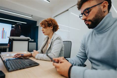 Multiracial Colleagues Attending A Business Lecture Analyzing Stats Discussing Strategy For