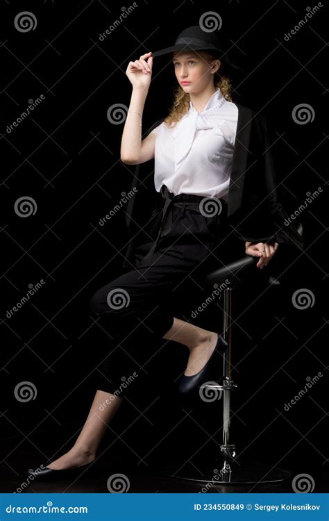 стильная девушка в черном костюме сидит на стуле Стоковое Изображение изображение