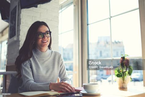 세련 된 커피숍에 앉아있는 동안 계획에 대해 생각 하는 안경에 꿈꾸는 젊은 작가 메모장 맛 있는 음료 한잔과 함께 레크리에이션 시간을 즐기면서 창 밖으로 보이는 아름 다운