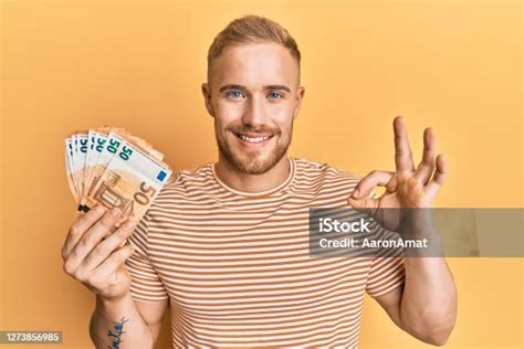 젊은 백인 남자 들고 무리의 무리를 들고 50 유로 지폐 와 확인 기호 와 손가락 미소 친절 한 제스처 우수한 기호 통화에 대한 스톡 사진 및 기타 이미지 Istock