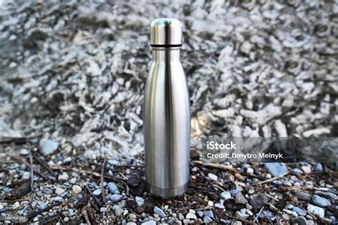 해변에서 재사용 가능한 강철 열병 복사 공간이있는 흐린 잔디의 배경에 은색의 강철 열수 병 플라스틱이 없습니다 폐기물이 없습니다 공간을 복사합니다 제로 폐기물 아니 플라스틱