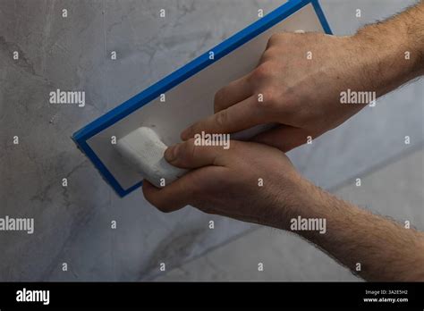 Worker Applying Grout On Ceramic Tiles Using A Rubber Float During Wall Tiling Process Hands