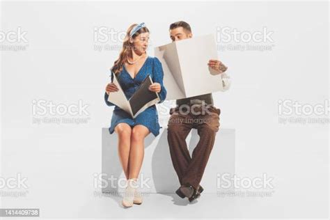 복고풍 의상을 입은 젊은 남녀가 함께 앉아 흰색 스튜디오 배경에 고립 된 잡지 또는 신문을 읽는 초상화 20 24세에 대한 스톡 사진 및 기타 이미지 Istock