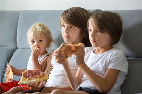 귀여운 아이들 소파에 앉아 피자를 먹고 Tv를보고 피자 파티에서 피자에서 물린 배고픈 아이 가정 생활에 대한 스톡 사진 및 기타 이미지 Istock