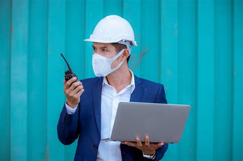 노트북 컴퓨터로 도크 컨테이너 창고에서 작업 및 생산 공정을 점검하는 인물 엔지니어 도크 작업자 안전 유니폼 및 안전 마스크 착용 상업 부두에 대한 스톡 사진 및 기타