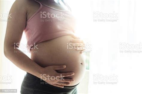 임신 한 여자는 그녀의 아이를 돌보는 동안 집에서 행복을 느낀다 임신 한 배에 아기를 들고 젊은 기대 어머니 출산 전 관리 및 여성 임신 개념 개념에 대한 스톡 사진 및