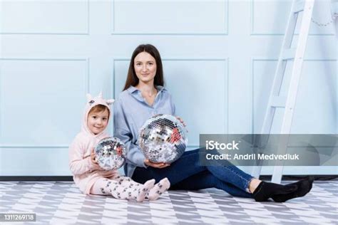 행복한 사랑의 가족 젊은 어머니와 유니콘 의상을 입은 어린 딸이 바닥에 앉아 파란색 벽 배경에 디스코 레이어를 가지고 놀고 있습니다 행복한 어머니의 날 아기의 날 2 3