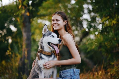 A Woman With A Husky Breed Dog Smiles And Affectionately Strokes Her