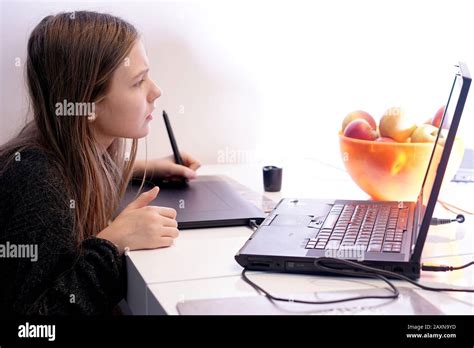 Girl At Home Learns To Draw On The Laptop Using A Tablet And Pen Stock Photo Alamy
