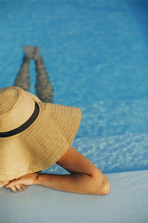 모자를 쓴 세련된 젊은 여성이 푸른 수영장에서 휴식을 취하고 여름 휴가를 즐기고 있다 고급 리조트에서 휴가를 보내는 햇볕을 쓴 소녀 옥상의 수영장에서 수영 최고의 전망