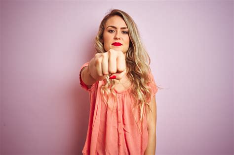 분홍색 고립 된 배경 펀치 주먹을 통해 서 티셔츠를 입고 젊은 아름다운 여자는 싸움 공격적이고 화가 공격 위협과 폭력 T 셔츠에 대한 스톡 사진 및 기타 이미지 Istock