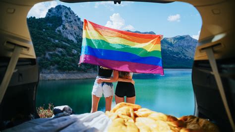 Lgbt 프라이드 축하 바람에 흔들리는 무지개 깃발 뒤에 함께 서 있는 두 명의 퀴어 여성 2명에 대한 스톡 사진 및 기타 이미지 Istock