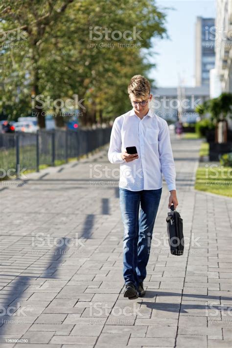젊은 남자는 손에 휴대 전화와 다른 손에 서류 가방을 들고 거리를 걷고 얕은 초점 거리에 대한 스톡 사진 및 기타 이미지 거리 걷기 남성 Istock