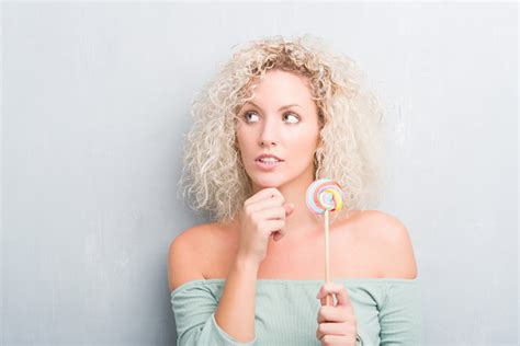 그런 지 회색에 젊은 금발의 여 자가 먹는 사탕 롤리팝 심각한 얼굴 생각 질문 매우 혼란 스 러 워 아이디어에 대 한 벽 개념에 대한 스톡 사진 및 기타 이미지 Istock