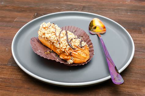 숟가락 주방 나무 테이블 설탕 음식 식기 식기 가정 요리가 있는 접시에 갓 구운 달콤한 크림 에클레어 달콤한 디저트 아침 프렌치 홈 아침 식사 클로즈업 가정 생활에 대한