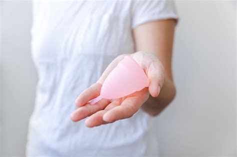 흰색 배경에 고립 된 분홍색 생리컵을 들고 있는 여성의 손 생리 기간에 여성 현대 대체 생태 부인과 위생 소녀 손에 혈액에 대한