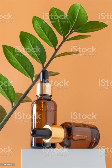 흰색 연단에 베이지 색 배경에 에센셜 오일 모형 아로마 테라피 대체 의학을위한 피펫이있는 갈색 유리 병에 화장품 의료 미용 제품 자연 향기로운 루틴 0명에 대한 스톡 사진