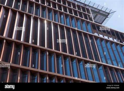 A Modern Building Facade Featuring A Geometric Pattern Of Vertical And Diagonal Metal Fins And