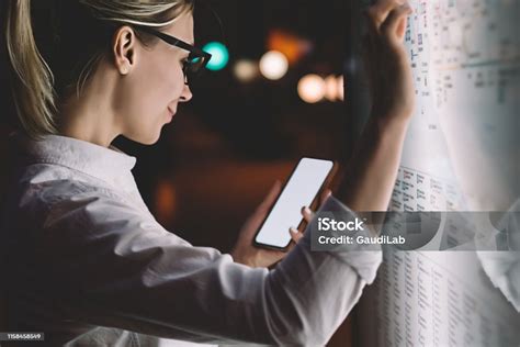 대중 교통 지하철지도와 디지털 모니터 손에 스마트 폰과 큰 디스플레이에 서 있는 여성 휴대 전화에 기차 일정 응용 프로그램을 사용하는 동안 손가락 화면으로 만지는 젊은 여자