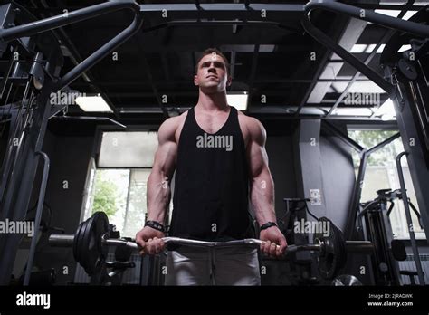 Low Angle Shot Of A Muscular Male Athlete Working Out With Ez Curl Barbell Doing Biceps