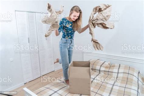 놀란 젊은 여자는 집에서 판지 상자를 풀고 침대에 서 있다 소포 배달 인터넷 주문 30 34세에 대한 스톡 사진 및 기타 이미지 30 34세 가정의 방 개회행사