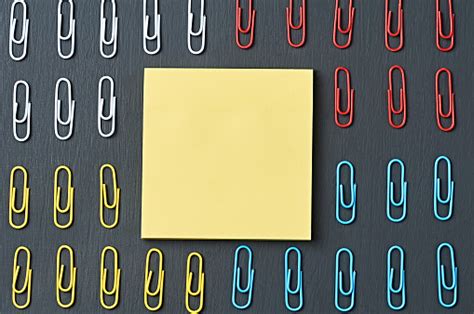 사무실 이나 교육에 대 한 많은 다른 종이 클립의 행의 네 섹션 및 중앙에 빈 사각형 스티커 어두운 긁힌된 콘크리트 테이블에 거짓말 클로즈업 텍스트를 위한 공간 개인