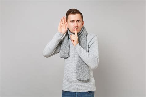 스웨터 스카프에 관심 있는 남자는 입술 쉿 제스처 도청 청각 회색 배경에 고립에 손가락으로 조용 하 게 자장 말한다 건강 한