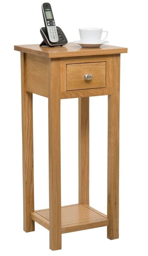 A Small Wooden Table With A Phone On Top Of It And A Cup Next To It