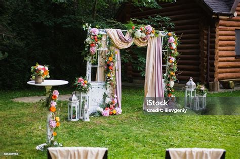 야외에서 아름다운 결혼식 장식 된 의자는 잔디에 서 있습니다 녹색 자연 배경에 천과 흰색과 분홍색 꽃으로 만든 웨딩 아치 오래된 문 소박한 스타일 꽃 식물에 대한 스톡 사진