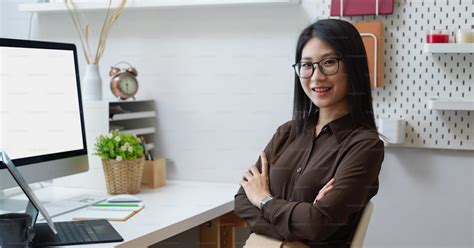 안경을 쓴 젊은 여성 회사원이 홈 오피스 룸에 앉아 있는 동안 카메라를 향해 웃고 있다 사진 Unsplash의 테이블 이미지