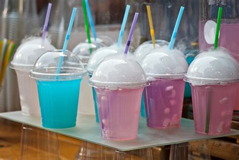 여러 가지 빛깔의 과일 음료 클로즈업 축제에서 플라스틱 컵에 무알코올 음료 주스와 채소를 곁들인 칵테일 하얀 연기가 칵테일로