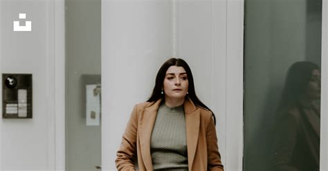 갈색 코트와 회색 바지를 입은 여자가 흰색 콘크리트 계단에 서 있다 사진 Unsplash의 무료 뉴욕 이미지