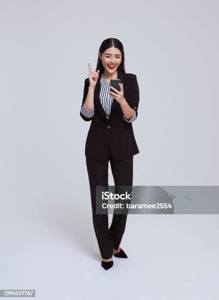아름답고 친절한 얼굴 아시아 사업가는 회색 배경 위에 휴대 전화를 들고 공식적인 양복을 입고 미소 짓습니다 25 29세에 대한 스톡 사진 및 기타 이미지 Istock