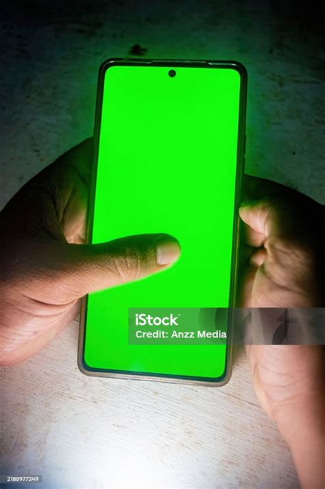 밝은 녹색 화면이 있는 스마트폰을 들고 있는 사람으로 장치의 디스플레이와 터치 상호 작용을 강조 표시합니다 기술 및 가제트 테마에 이상적 Brand Name Smart
